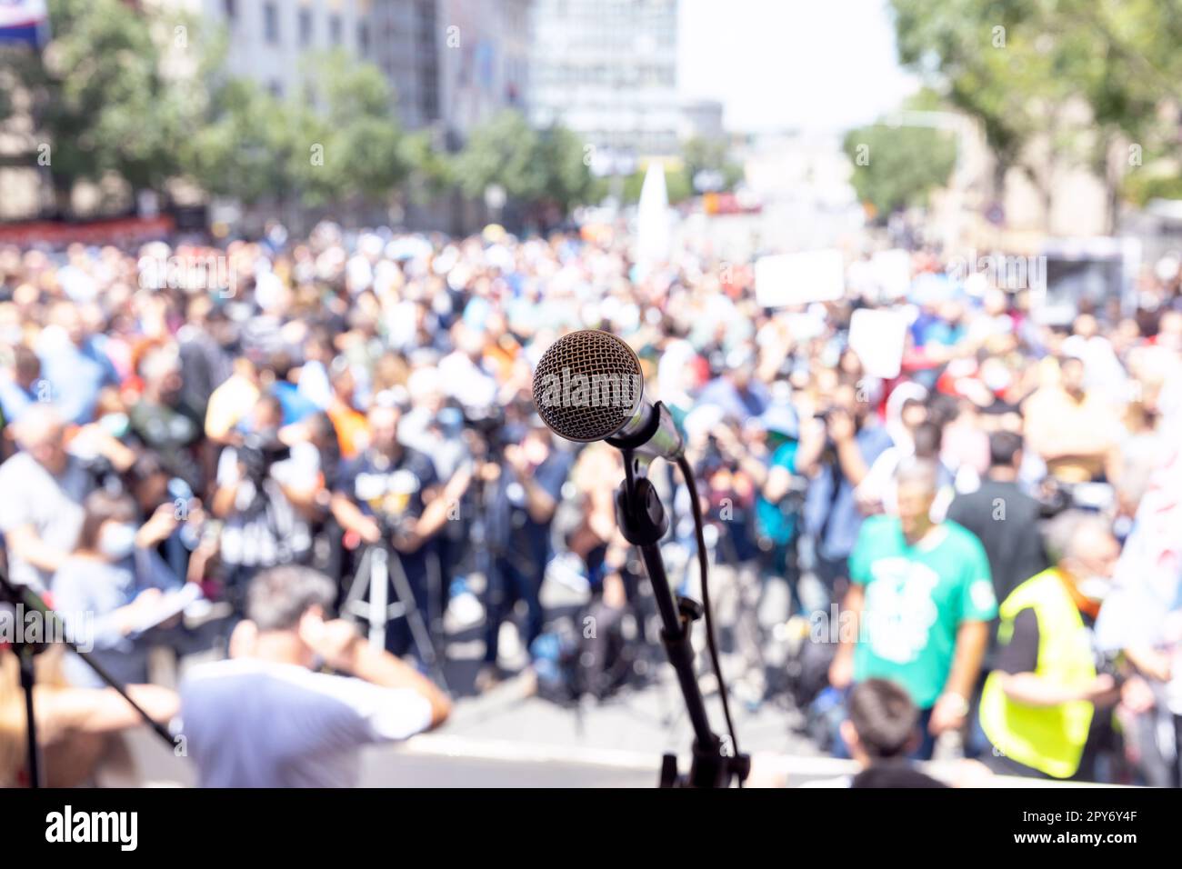 Focus on microphone, blurred group of people at mass protest against ...