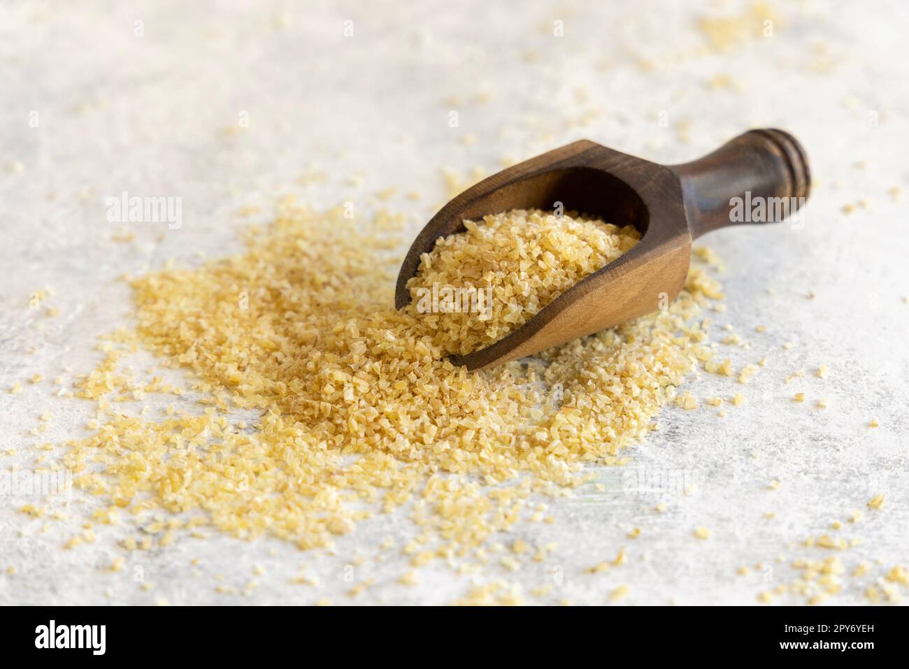 Wooden scoop of Dry uncooked bulgur wheat grain close up, copy space ...