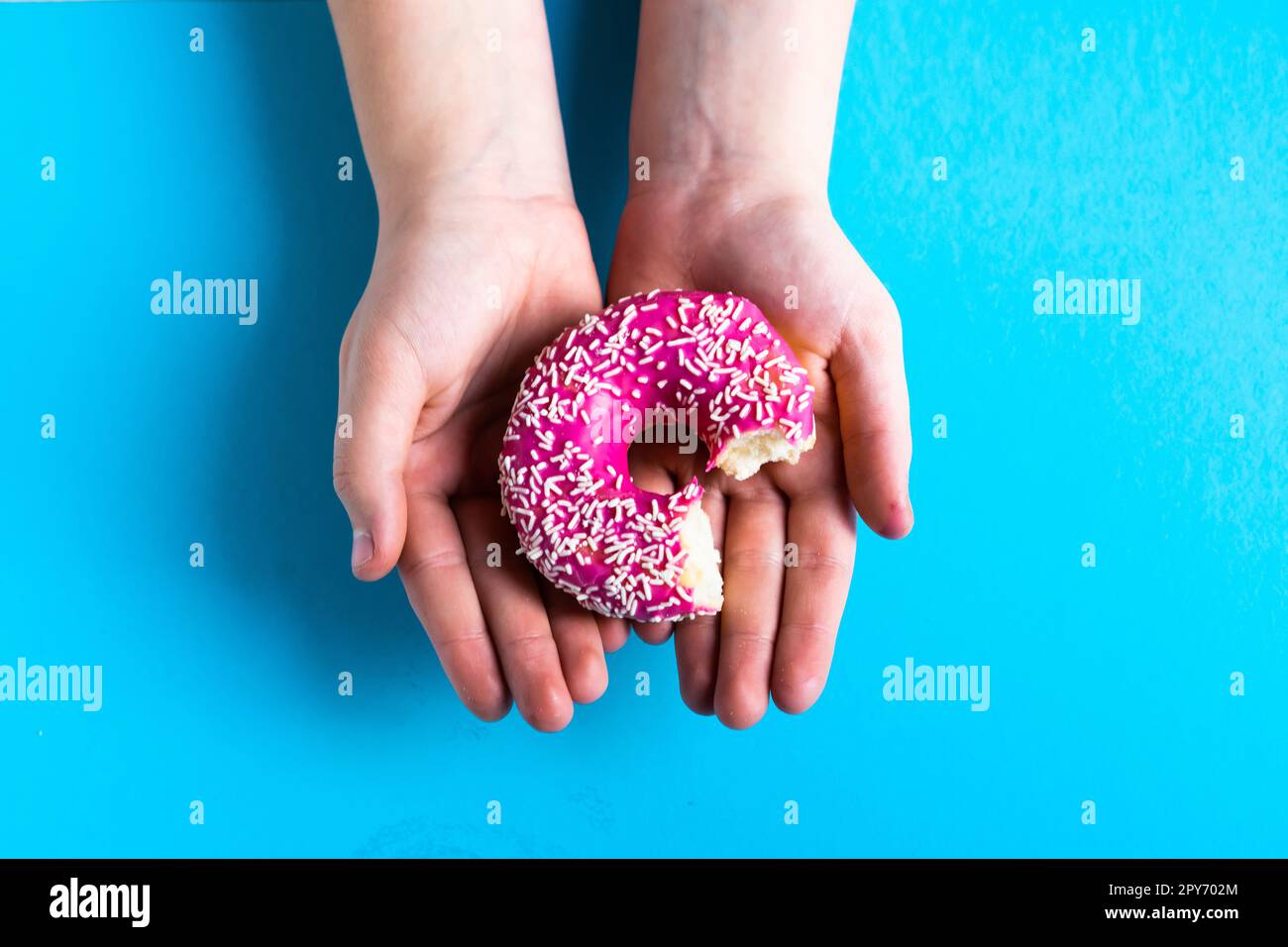 Hand holding a half eaten sweet pink donut isolated. Half eaten donut ...