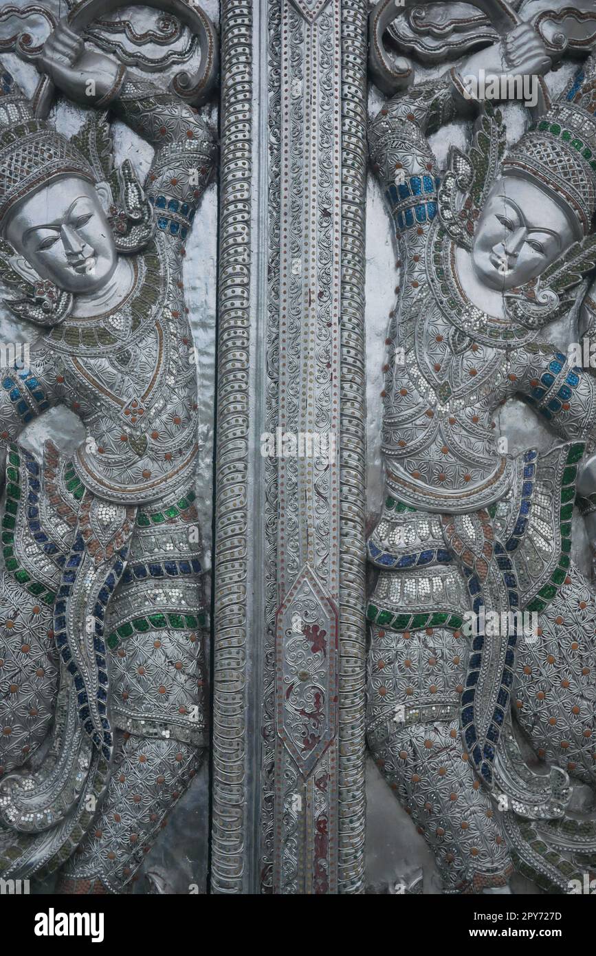 Twin apsara Buddhist deities on silver temple door in Thailand Stock ...