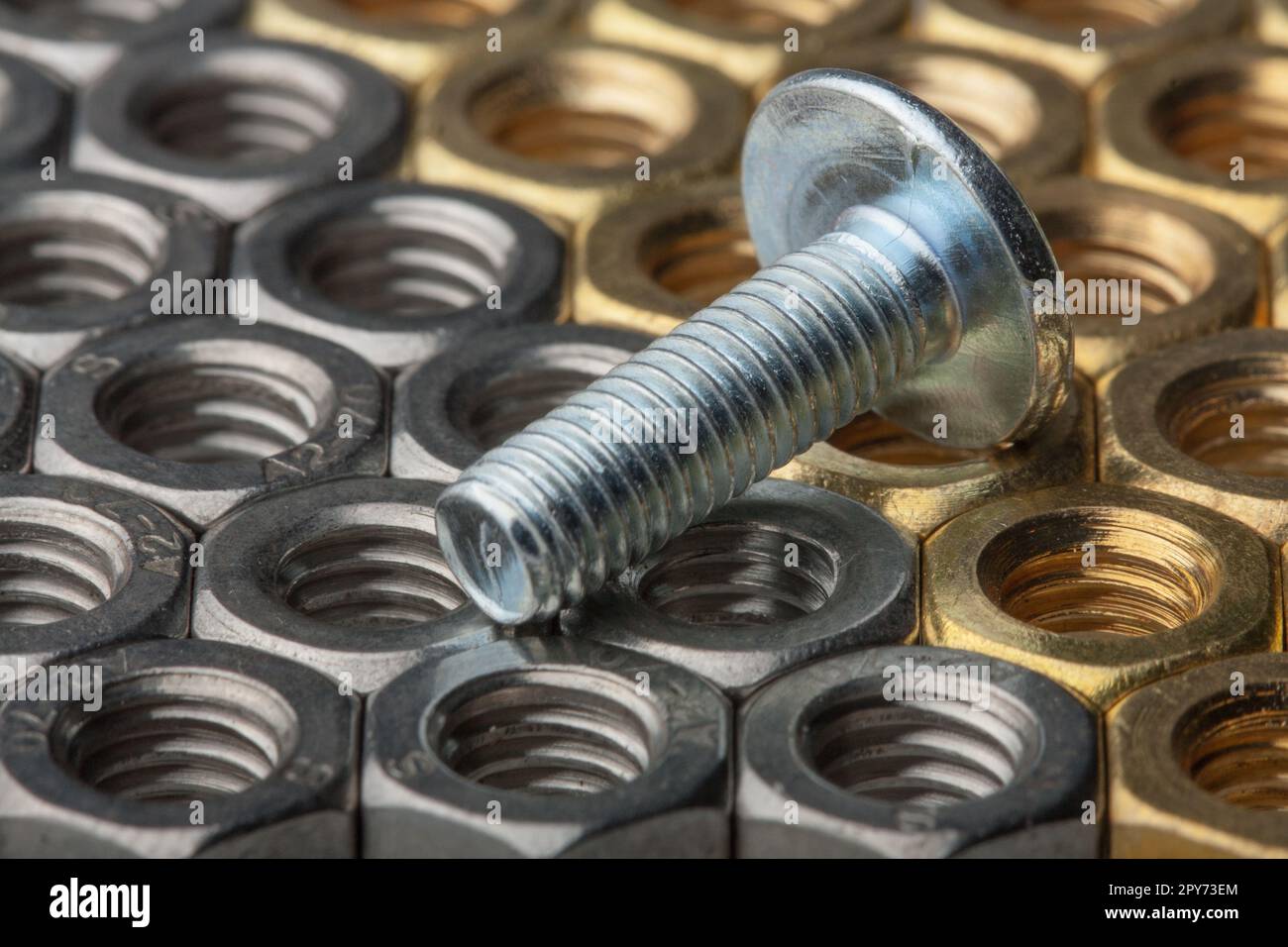 Metallic hex nuts and a fastener bolt with rivet, industrial background ...