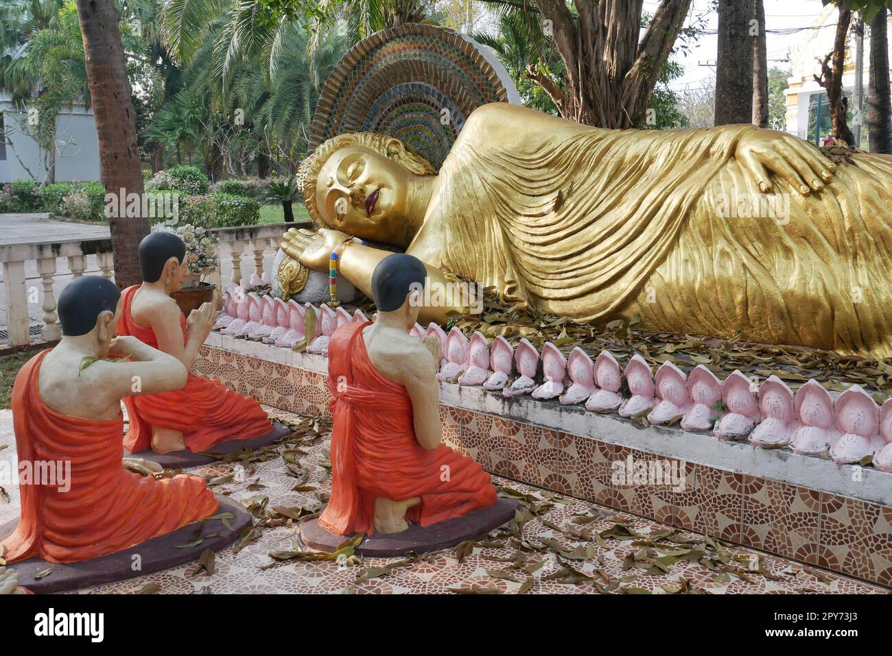 Statues of seated monks meditating before a golden reclining Buddha in ...