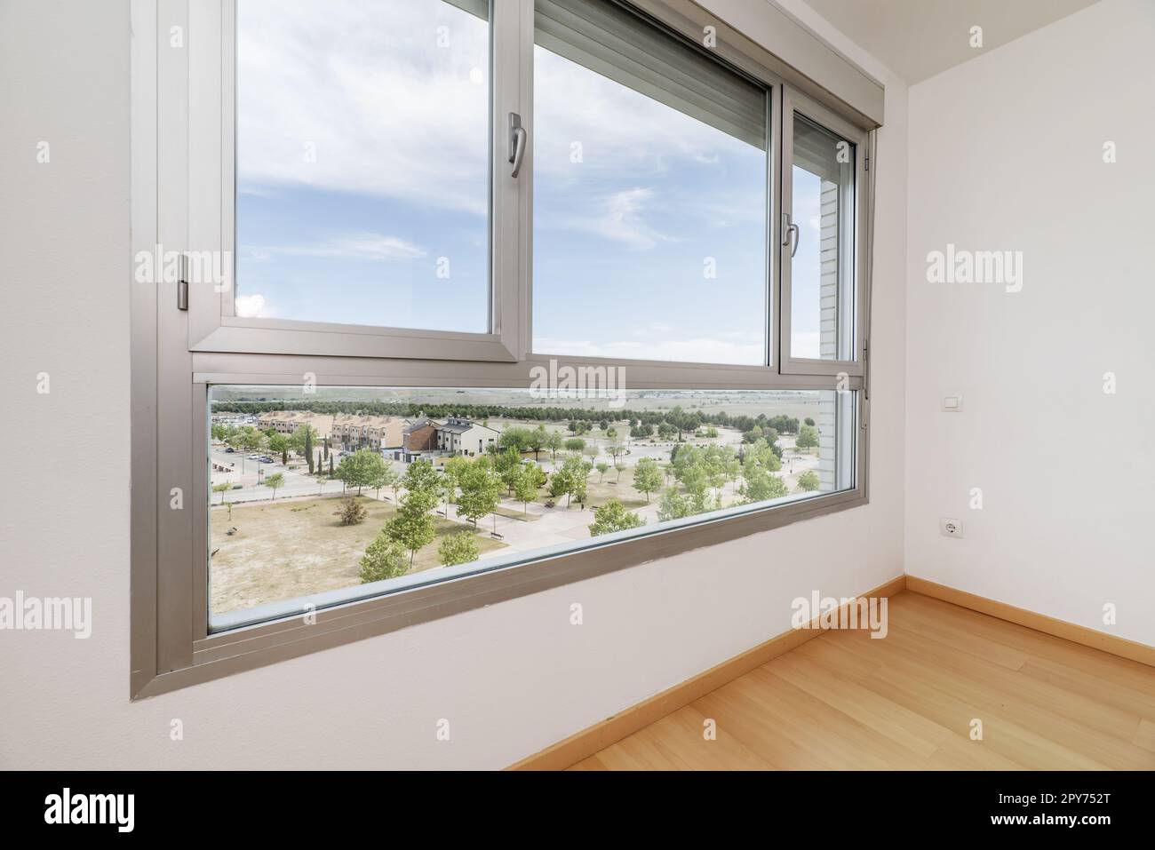 An empty room with a large window with unobstructed views of a park ...