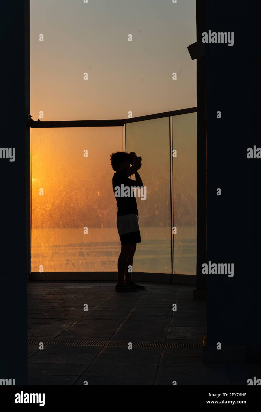 A young photographer taking a picture of the sunrise with a film camera ...