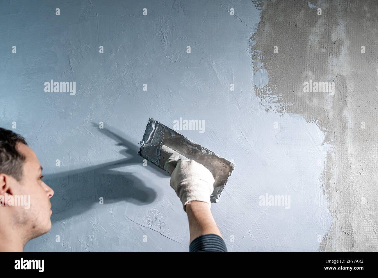 man applies insulation to a bathroom wall with trowel Stock Photo - Alamy