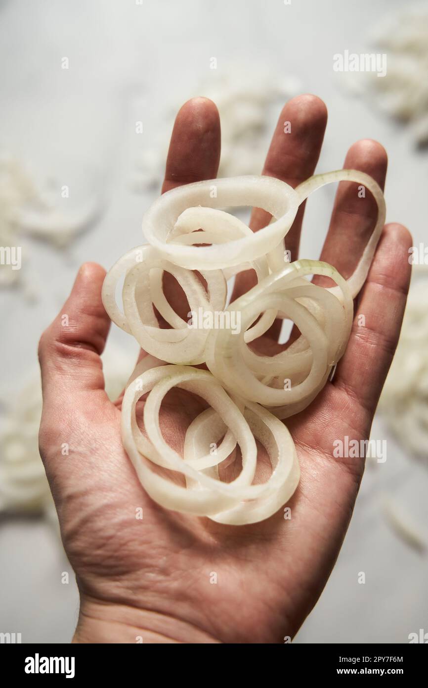 Ring sliced onions on mans hand. Photo show how does onion sliced into ...