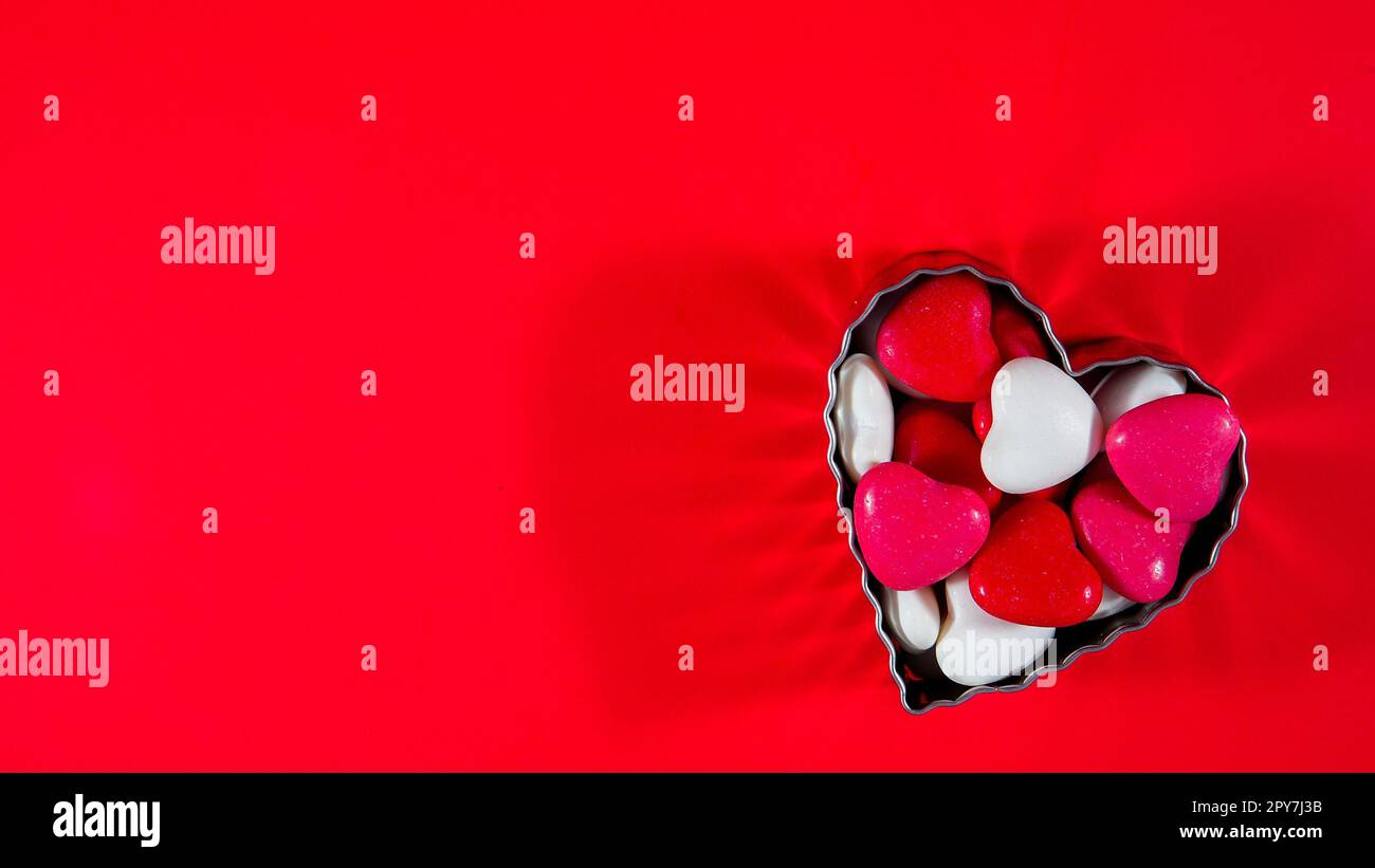 Heart shaped candy in form on red background Stock Photo - Alamy