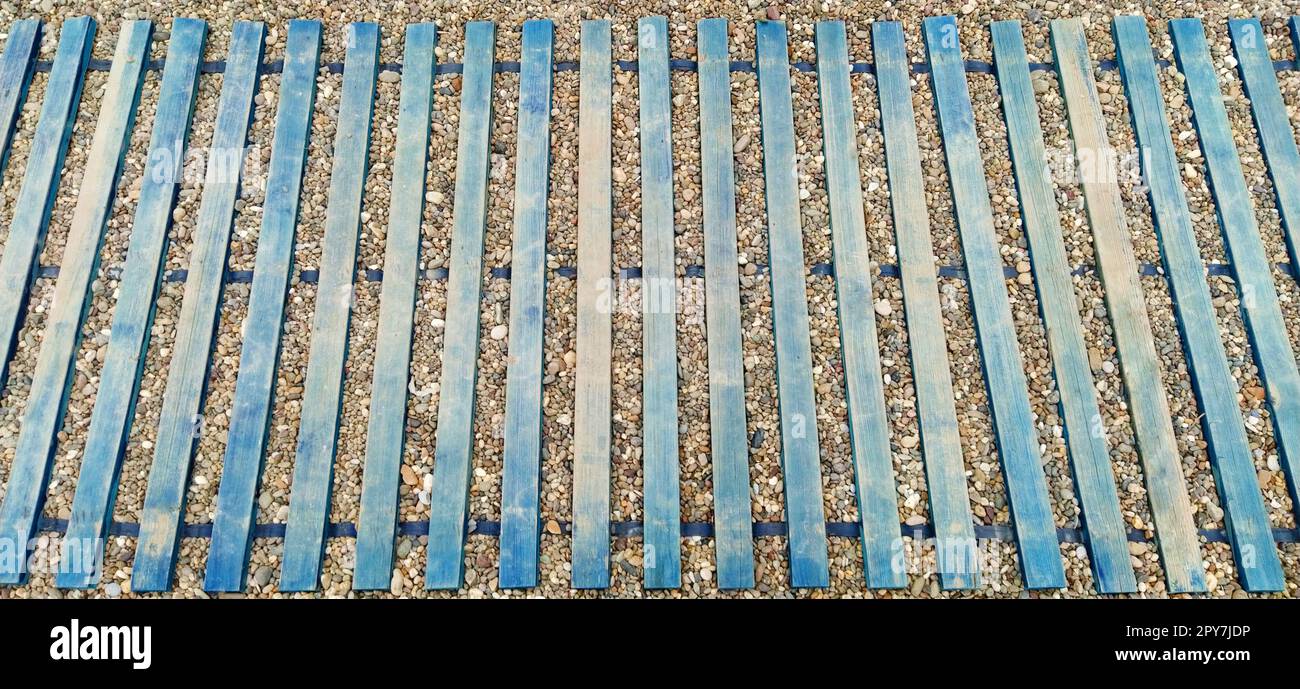 Wooden boardwalk on the beach. Sticks and boards on rocky ground. Heel ...