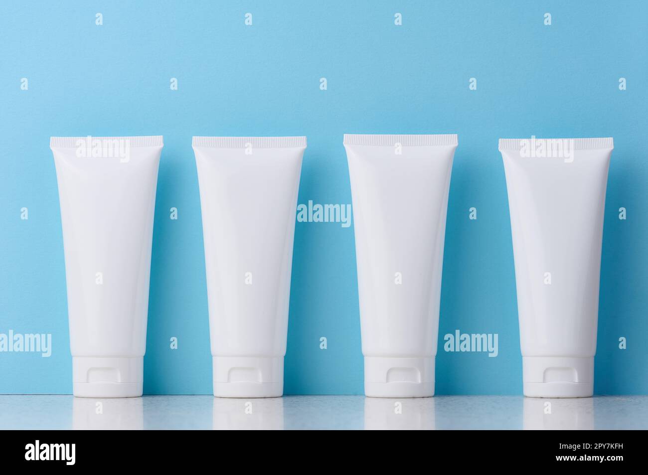 White plastic tubes for cosmetic products on a blue background ...