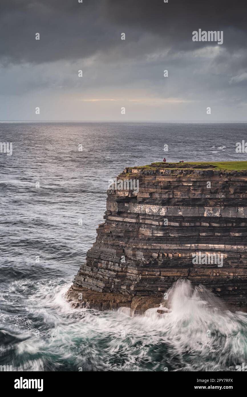 Fisherman standing on the edge of tall Downpatrick Head cliffs, Ireland ...