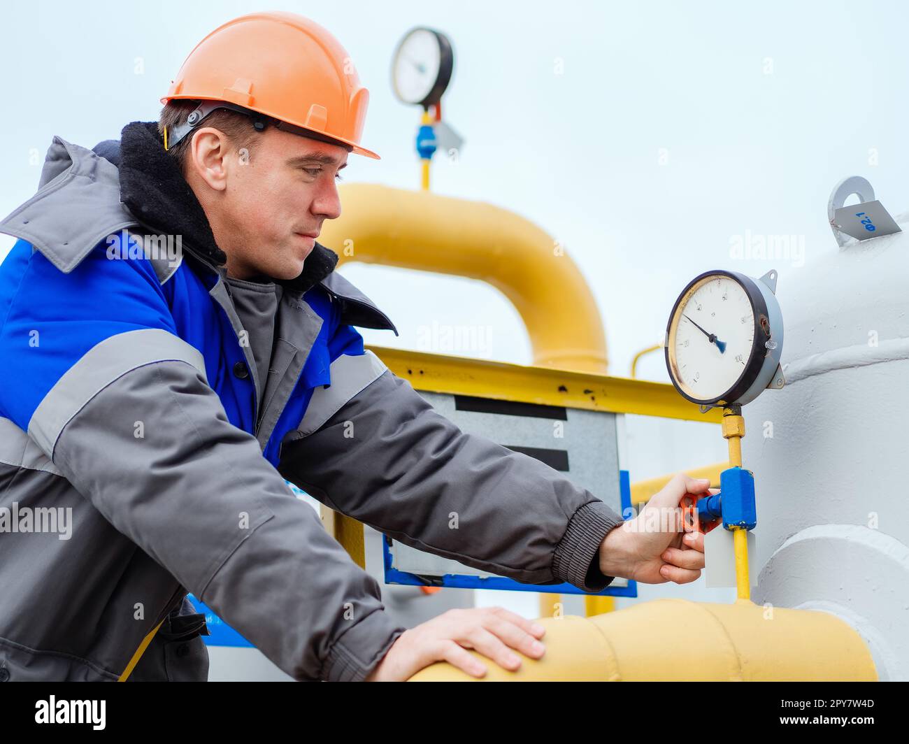 Caucasian worker at gas distribution station opens valve on gas supply ...