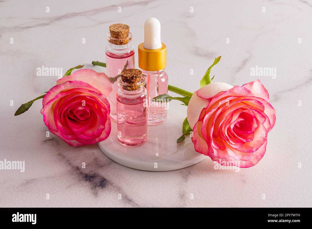 cosmetic product and bottled rose water with cork on a white marble ...