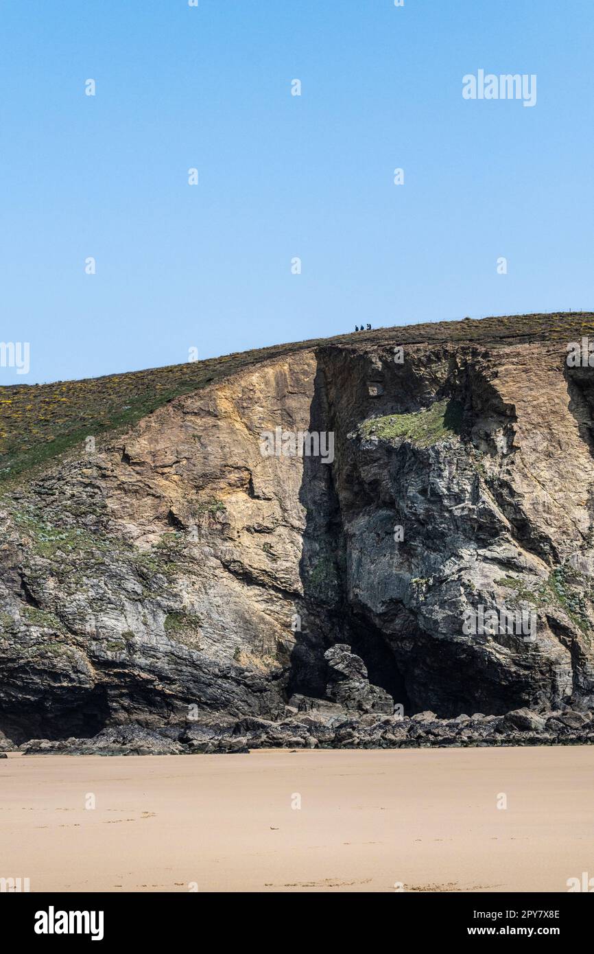The tiny figures of walkers walking above the rtowering ugged cliffs ...