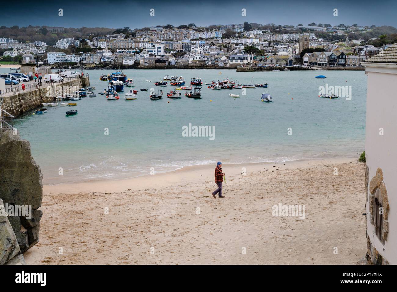 UK weather. A man walking alone on the beach on a rainy chilly ...
