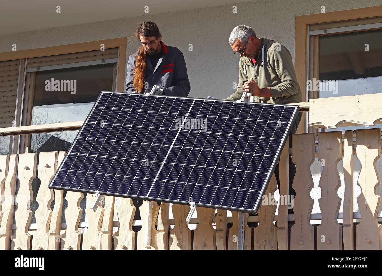 Two men assemble a balcony power plant to generate electricity Stock ...
