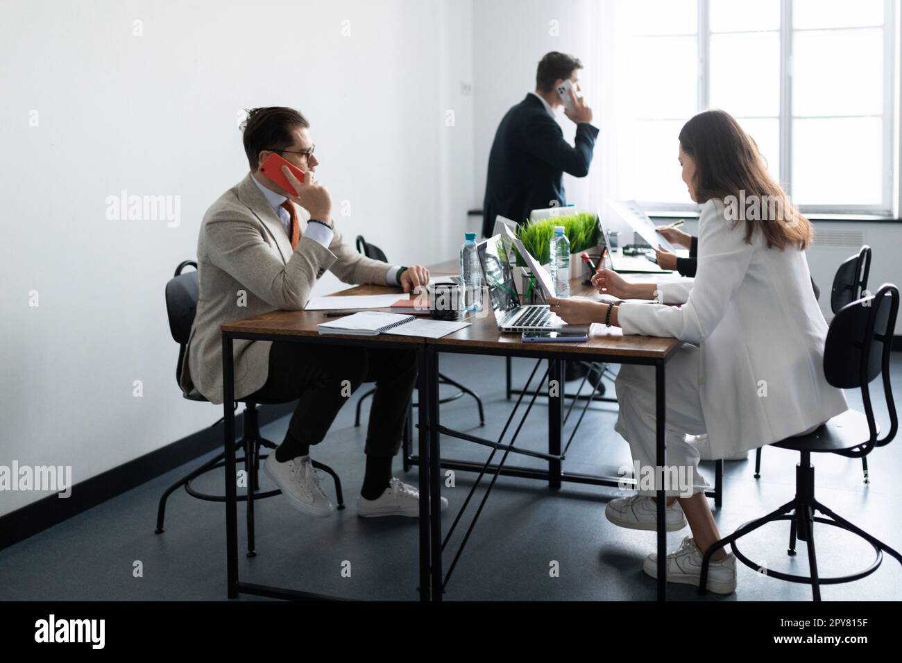 office staff talking on the phone while sitting at a common table Stock ...