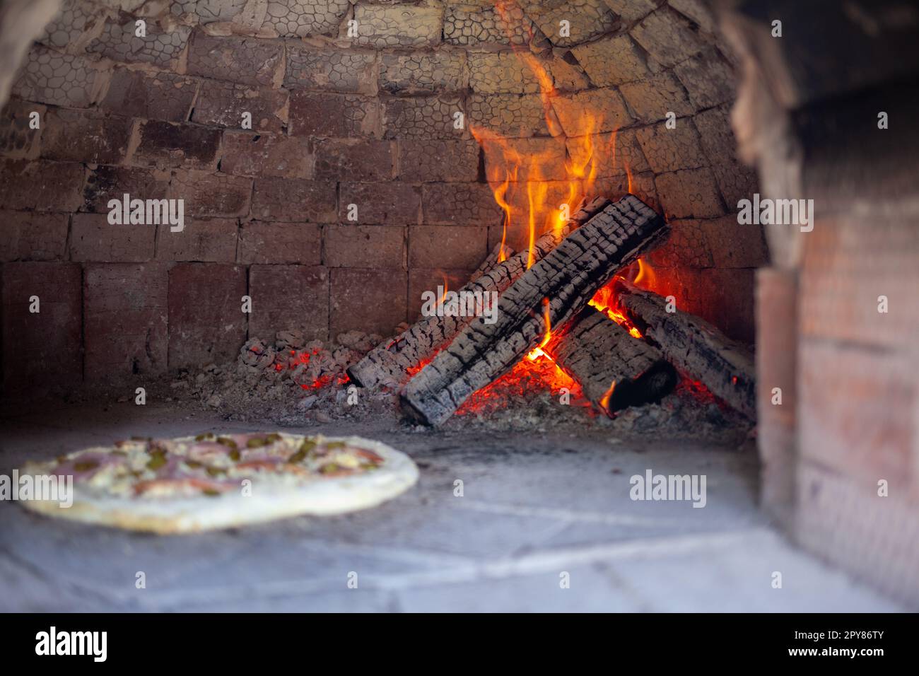 Cooking real pizza in a brick oven. Wood and fire are burning in the ...
