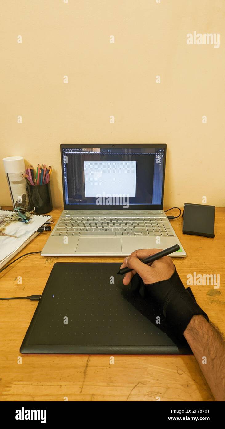 a designer person working on his laptop using a sketching tablet and ...