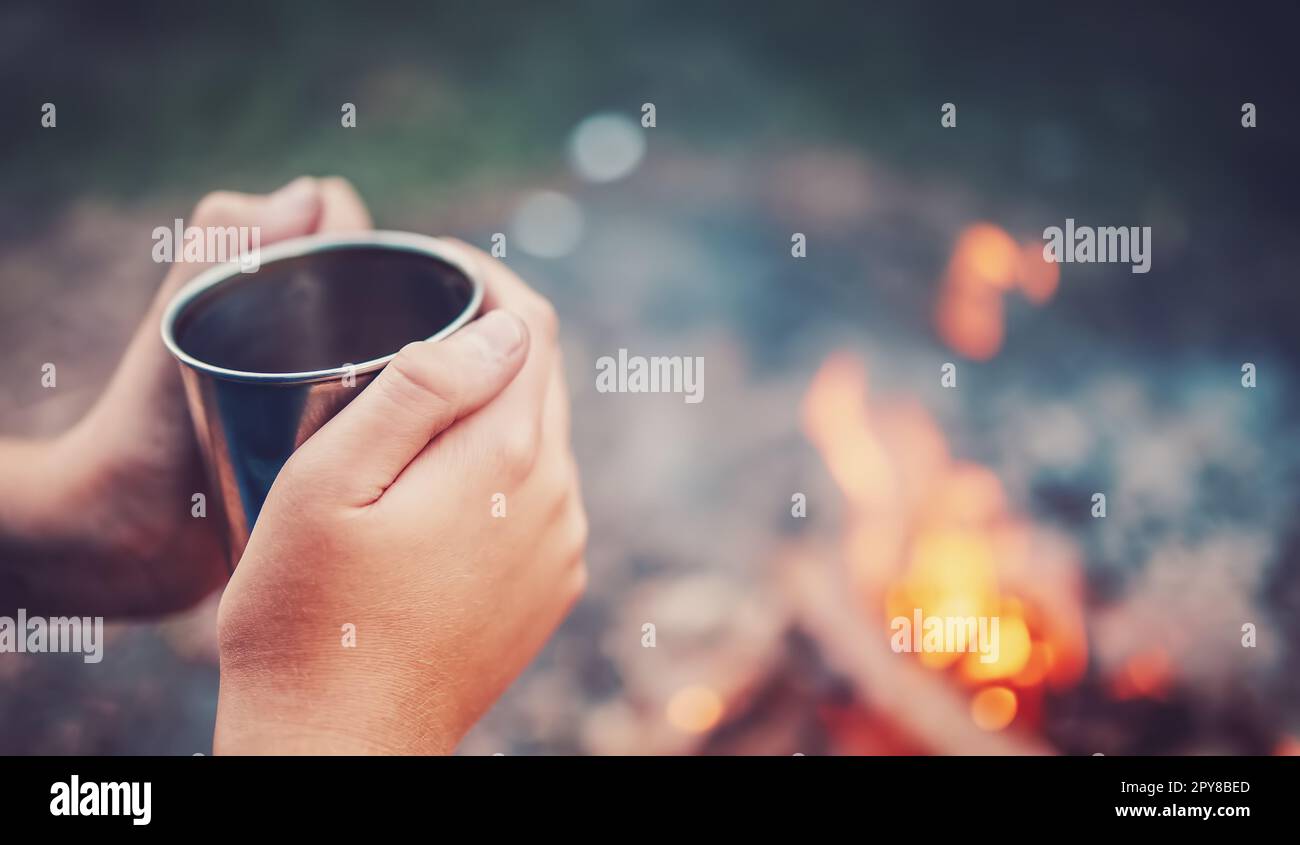 Human's hands holding the metal cup with hot drink above the fire Stock ...