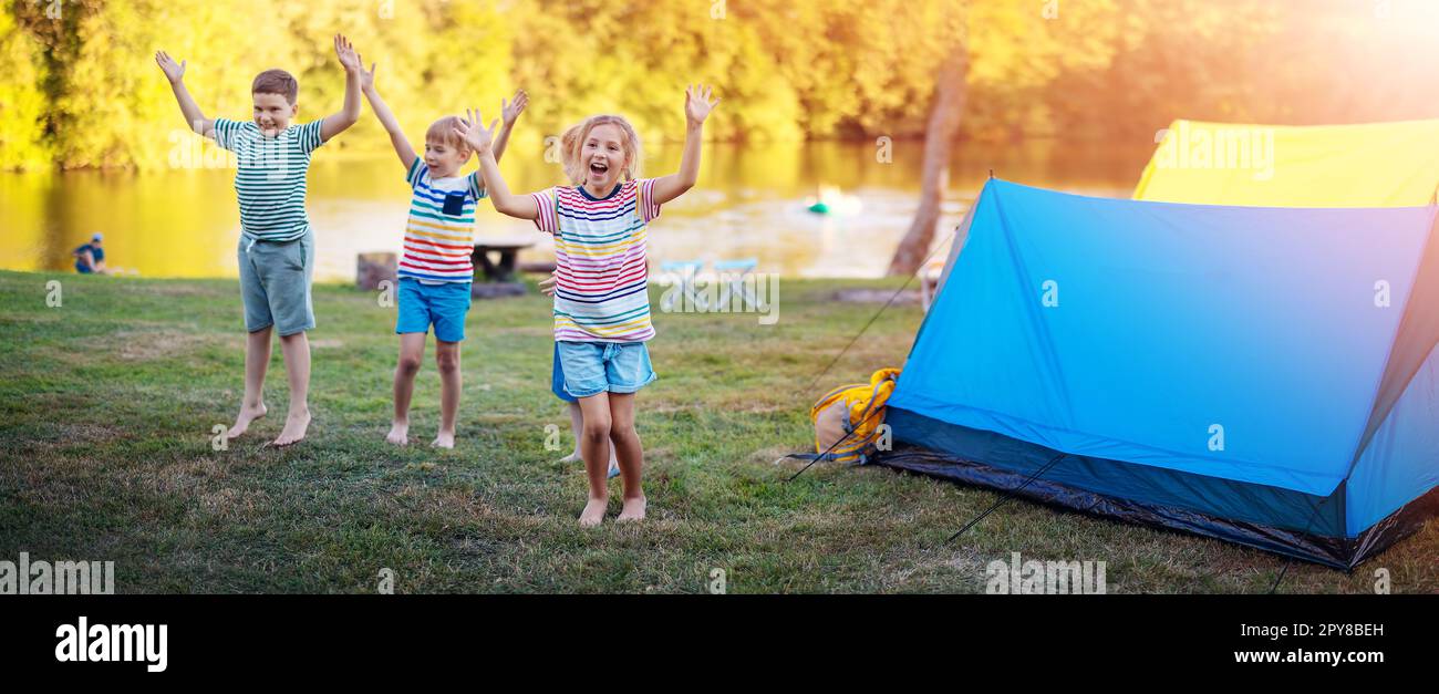 Group of four children playing near colourful tents in nature Stock ...