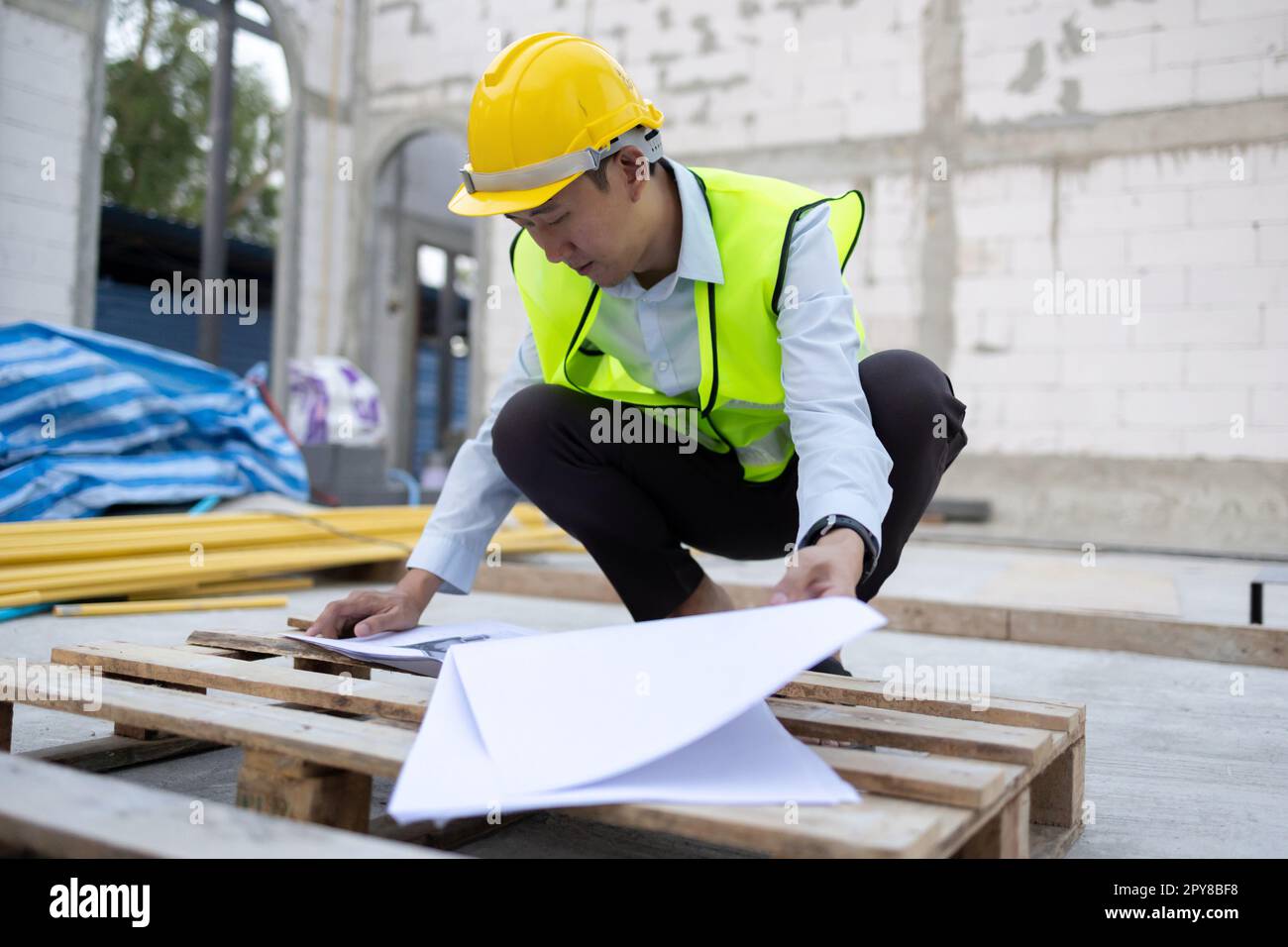 Young Asian engineer in engineering uniform and helmet at construction ...