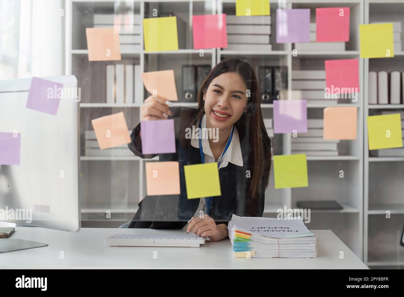 Happy business female planning ideas on a glass wall with colorful ...