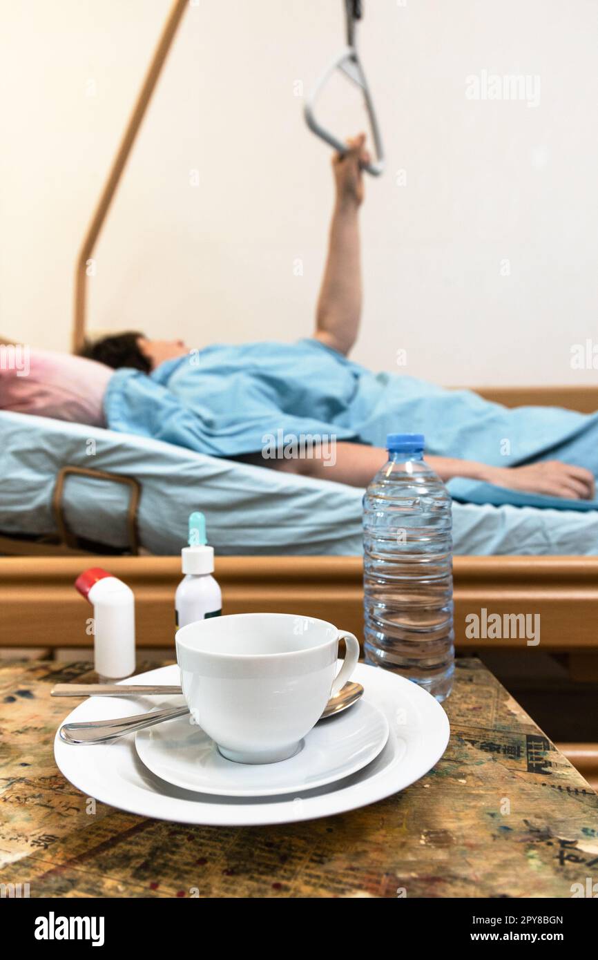 dishes on table and patient holding handle on bed Stock Photo - Alamy