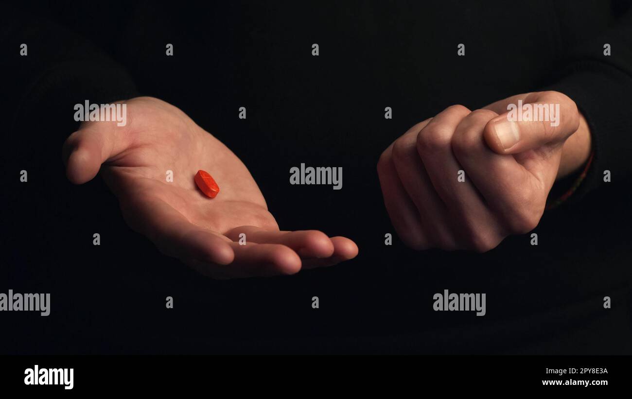 Studio shot male hands show red pill isolated on black background ...