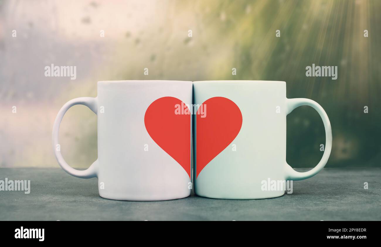 Mug couple with a huge heart on a window sill cuddle, cup of coffee ...