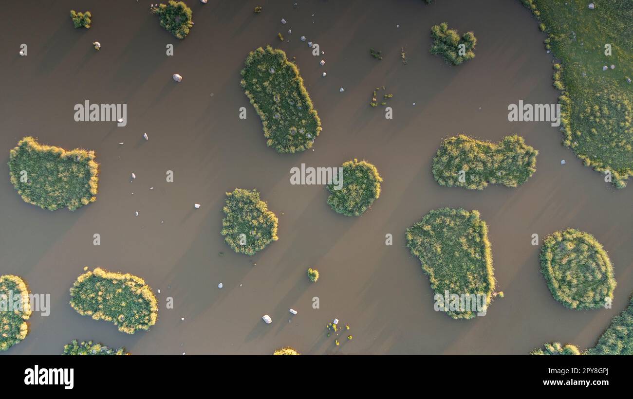 An aerial shot of a coastal lagoon with reed islands and small boulders ...