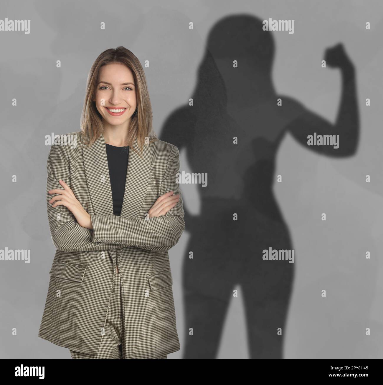 Businesswoman and shadow of strong muscular lady behind her on grey ...