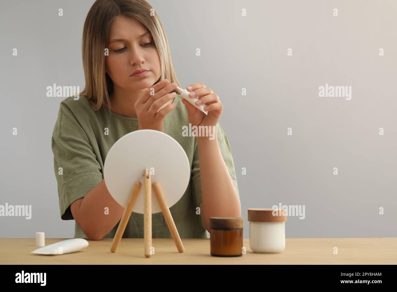 Sleep deprived young woman covering up dark circles with concealer near ...