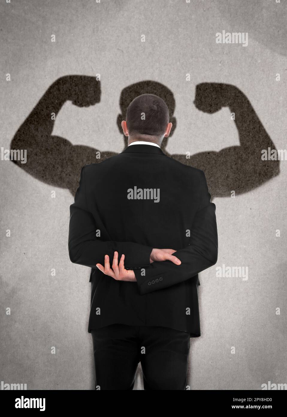 Businessman and shadow of strong muscular man in front of him on grey ...