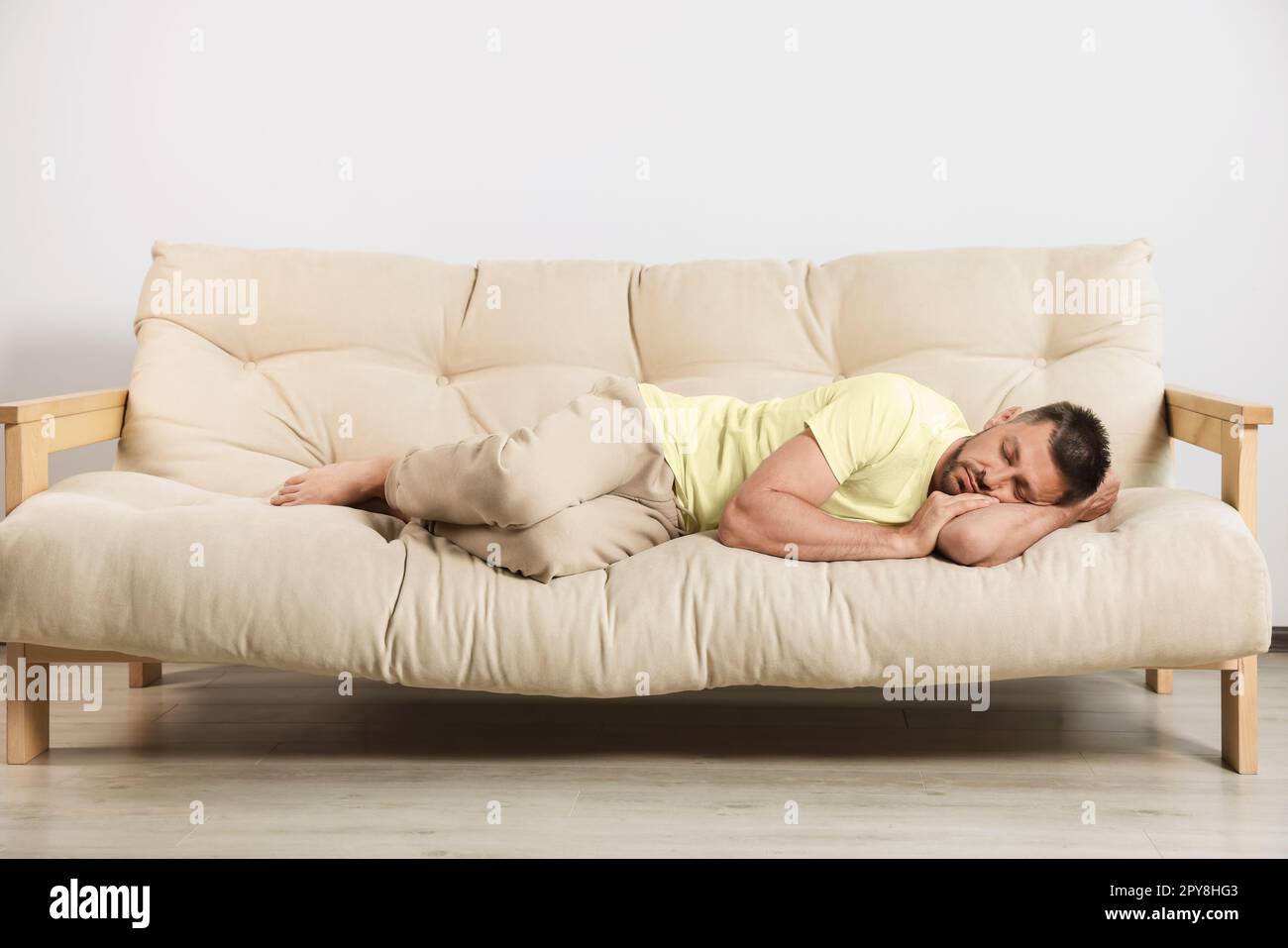 Tired man sleeping on sofa at home Stock Photo - Alamy