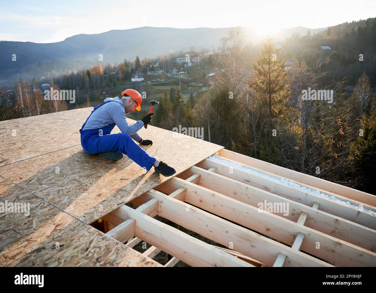 Carpenter hammering nail into OSB panel on the roof top of future ...