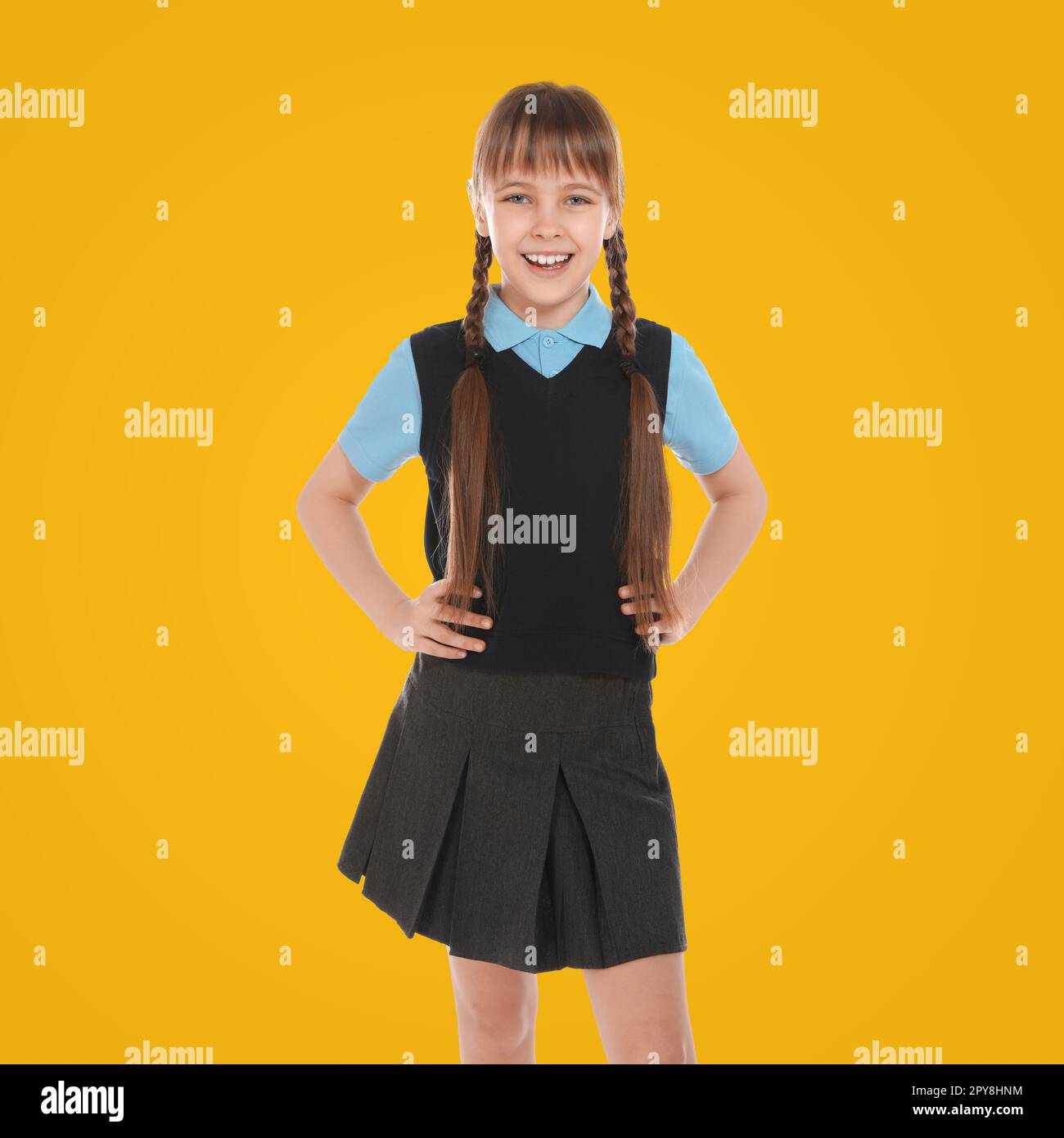 Portrait of cute girl wearing school uniform on yellow background Stock ...