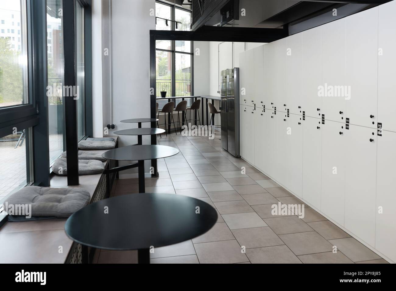 Hostel dining room interior with modern furniture and white lockers ...
