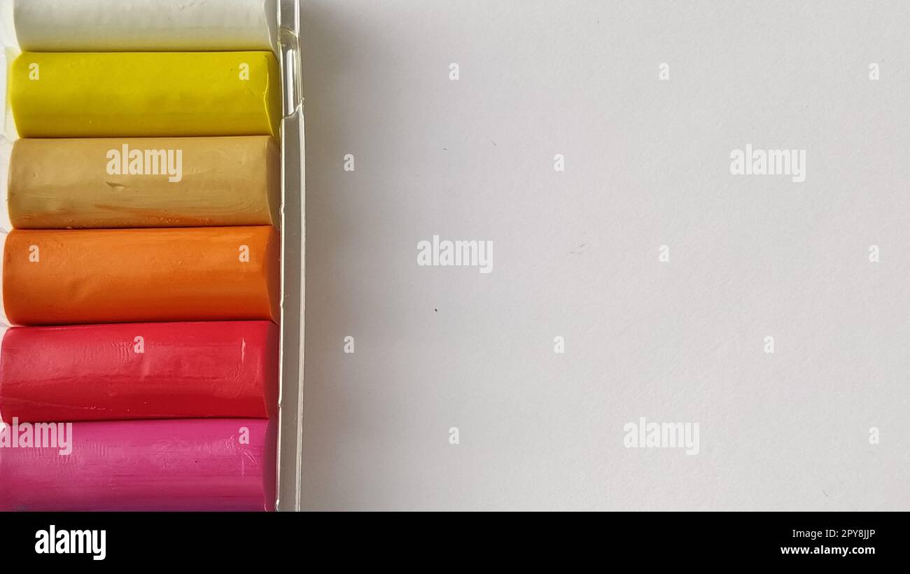 Multi-colored plasticine in plastic packaging on a white background ...