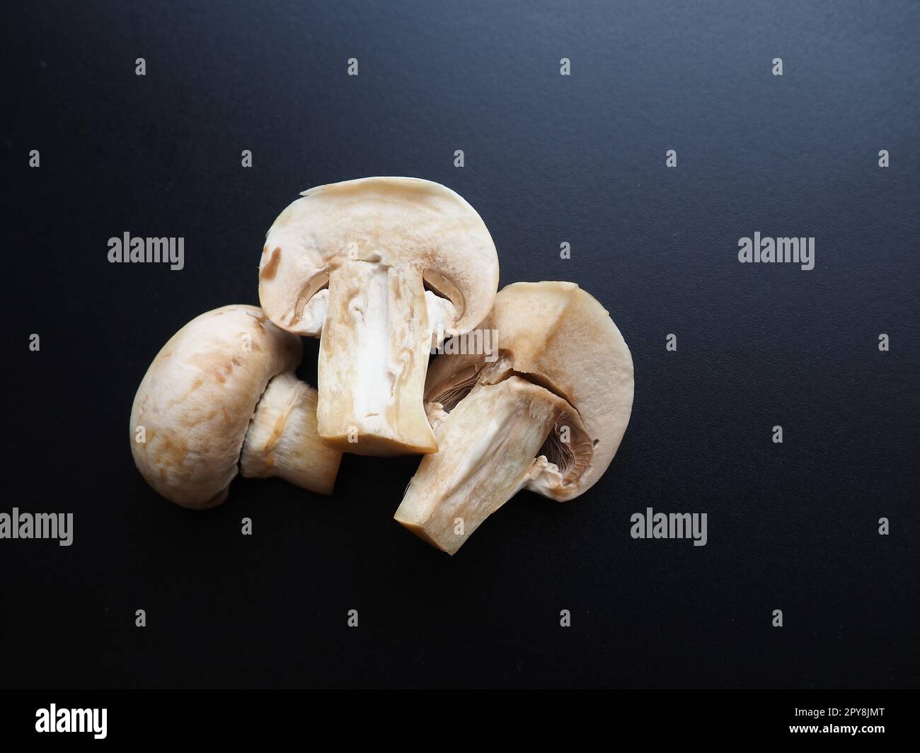 Champignons on a black background. Sliced and whole fresh uncooked raw ...
