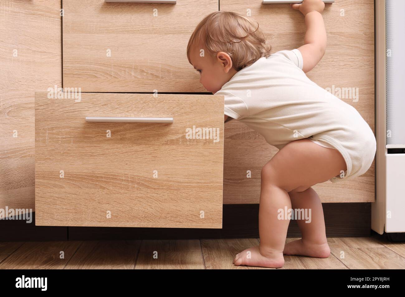 Little child exploring drawer indoors. Danger situation Stock Photo - Alamy