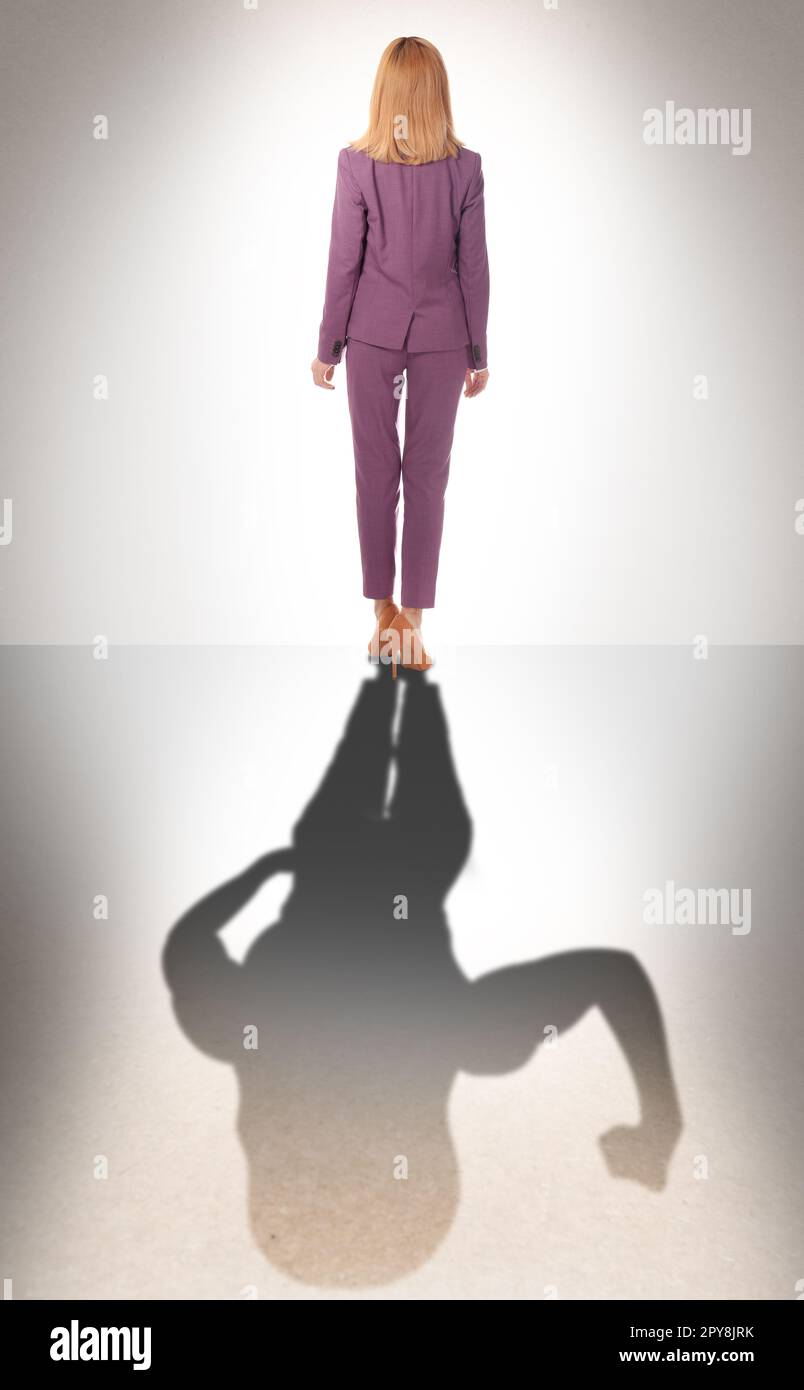 Businesswoman and shadow of strong muscular lady behind her on light ...