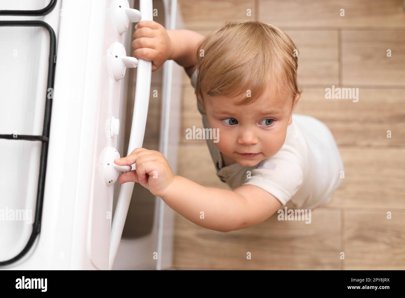 Little child playing with gas stove indoors, above view. Dangers in ...