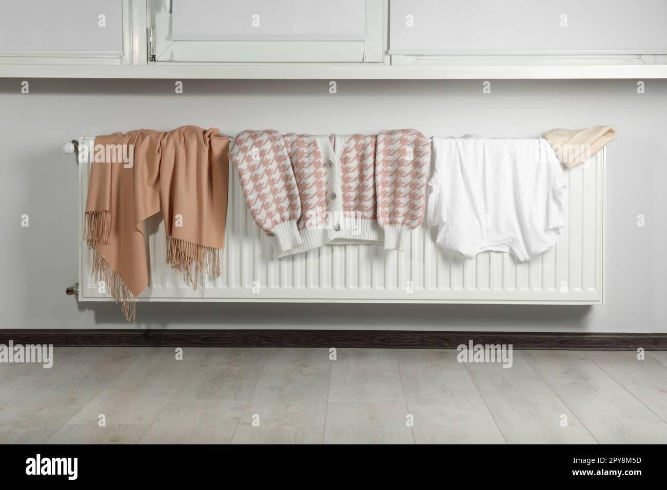 Clean clothes on heating radiator near window indoors Stock Photo - Alamy