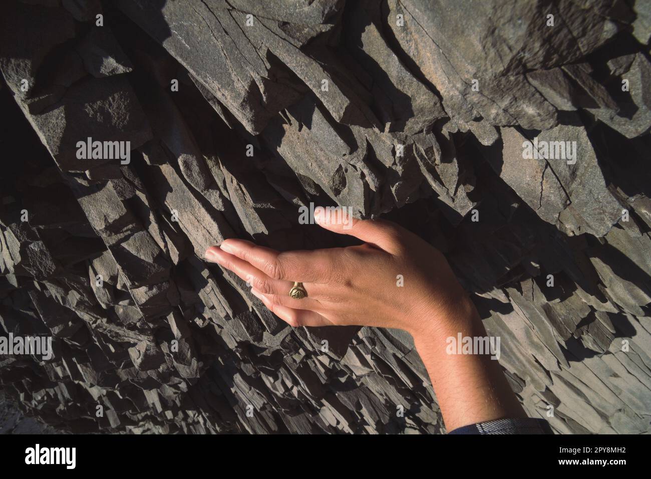 Close up female hand touching basalt rock concept photo Stock Photo - Alamy