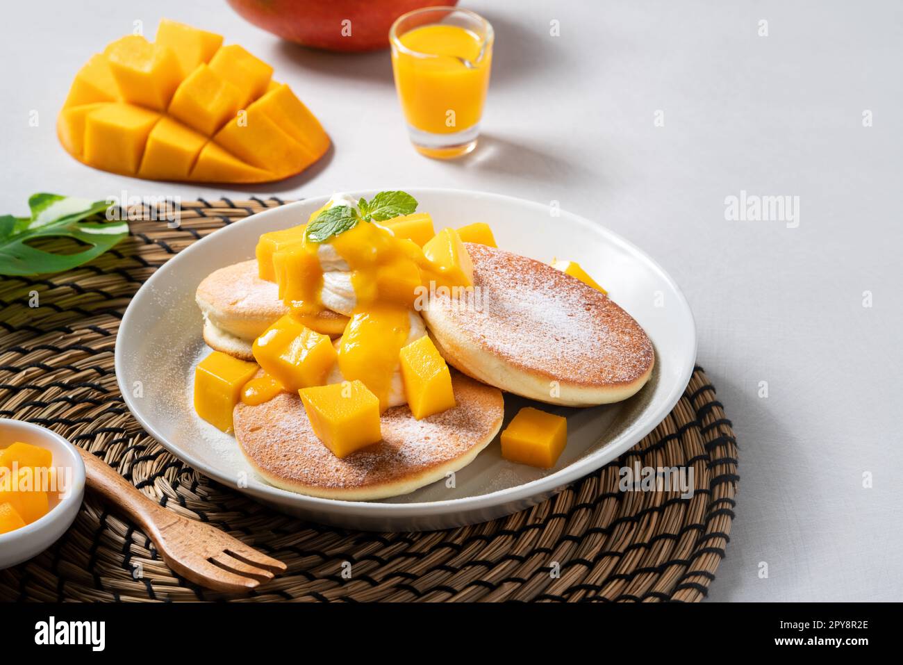 Delicious Japanese souffle pancake with dice mango fruit pulps and jam on gray table background ...