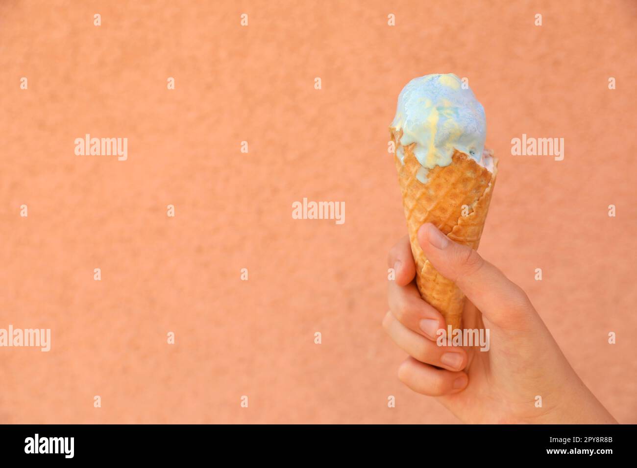 Woman holding delicious ice cream in wafer cone near coral wall ...