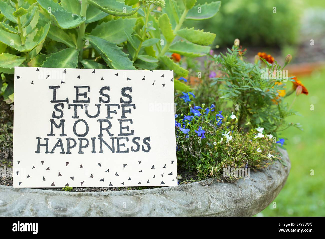 Card with phrase Less Stuff More Happiness on stone planter outdoors ...