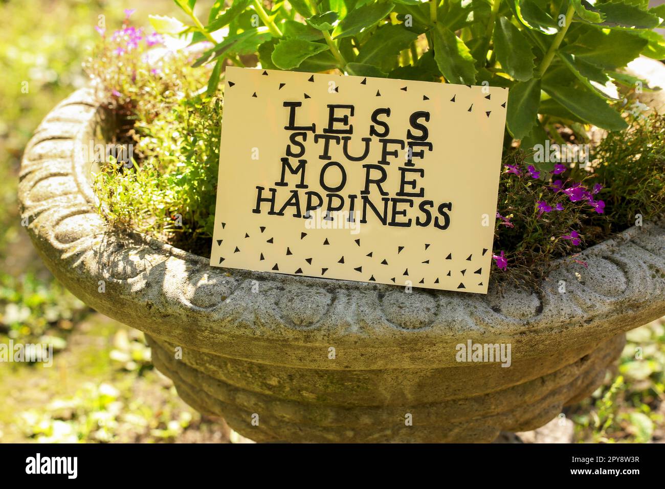 Card with phrase Less Stuff More Happiness on stone planter outdoors ...