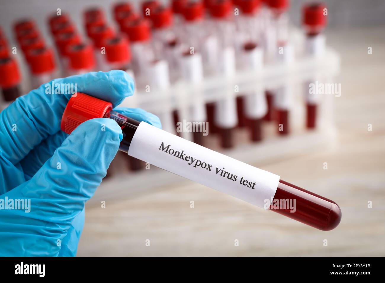 Laboratory worker holding test tube with blood sample near rack ...
