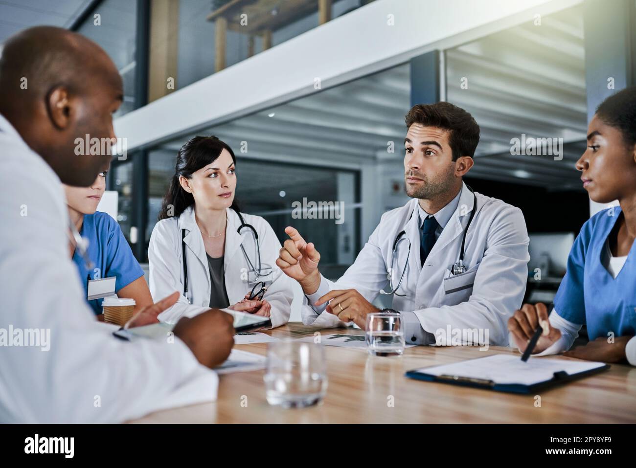 Lets discuss diagnosis. a group of doctors having a meeting in a ...